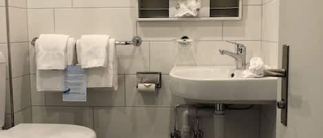 Uma casa de banho moderna com sanita, lavatório e espelho.