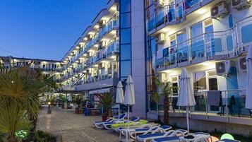Um hotel com vários andares, varandas, área de estar externa e cadeiras de lounge.