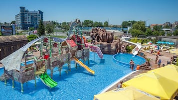 Parque aquático com toboáguas e piscina, cercado por edifícios e árvores.
