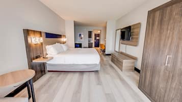 Quarto de hotel moderno com uma cama grande, uma escrivaninha, uma TV na parede e um guarda-roupa.
