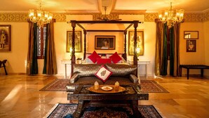 Um quarto luxuoso com cama de dossel, lustres elaborados e uma lareira clássica.