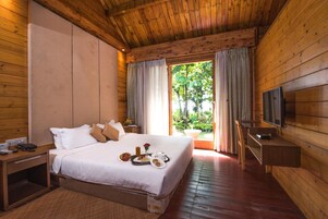 Um quarto rústico estilo cabana, com cama, mesa de cabeceira, televisão e janela com cortinas.