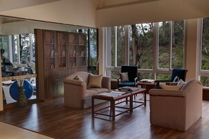 Uma sala de estar ampla com uma janela grande, uma estante de livros e dois sofás.