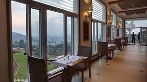 Uma sala de jantar com janelas amplas, mobiliário de madeira e vista para a paisagem.