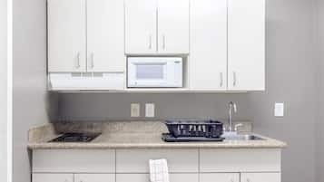 Um frigorífico/congelador grande, um micro-ondas, uma cafeteira/bule