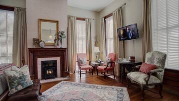 Uma sala de estar tradicional com lareira, dois poltronas, um sofá e uma televisão.