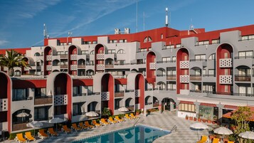 Um hotel com piscina, várias varandas e esquema de cores em vermelho e cinza.