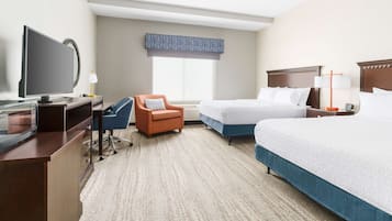 Quarto de hotel com uma cama grande, uma mesa de trabalho com televisão, uma cadeira e uma janela com vista.