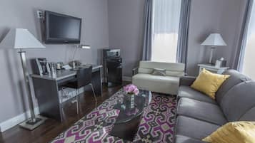 Uma sala de estar moderna com sofá, mesa de centro, TV, escrivaninha e micro-ondas.