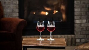 Uma lareira com dois copos de vinho tinto sobre uma mesa pequena.