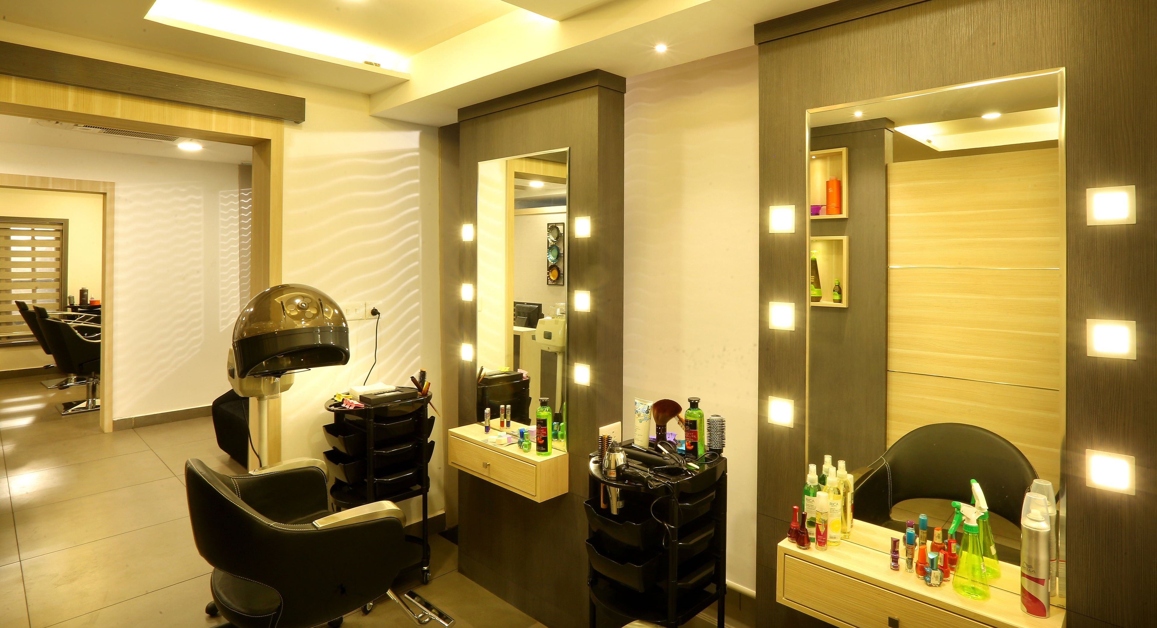 Um salão de beleza moderno com um espelho grande, secador de cabelo e diversos produtos para cabelo no balcão.
