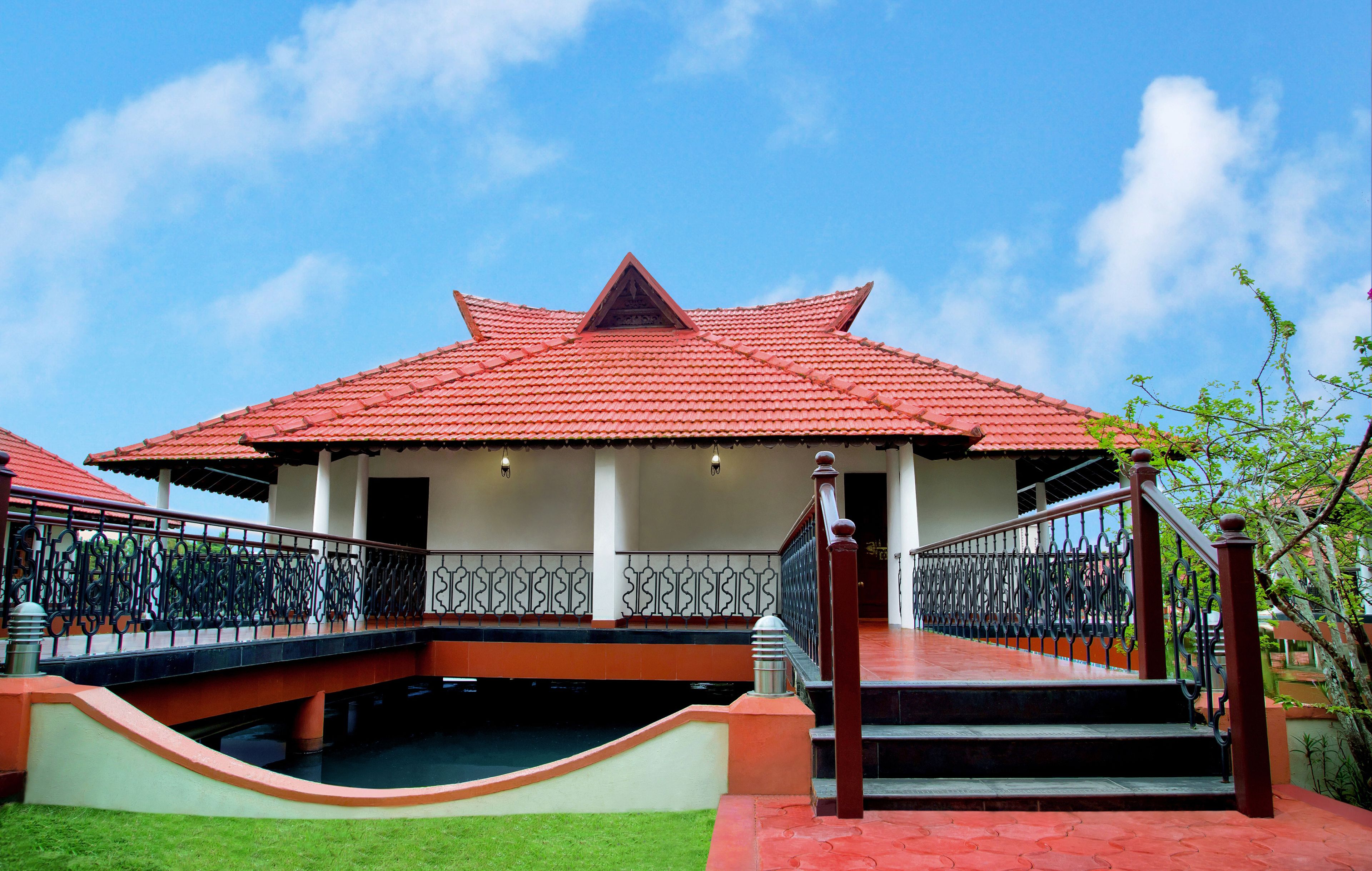Um edifício com telhado de telhas vermelhas, uma escadaria com corrimão e uma pequena área de piscina.
