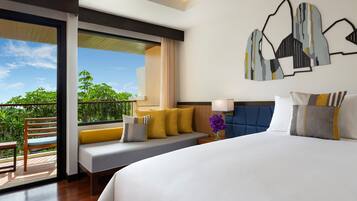 Quarto de hotel com uma cama grande, um sofá com almofadas amarelas, vista para área verde e uma obra de arte abstrata moderna na parede.