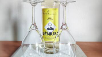 Uma garrafa de vinho Geniust com dois copos de vinho vazios em um tabuleiro.