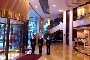 Um saguão de hotel com uma escadaria imponente, uma recepção e entrada em vidro.