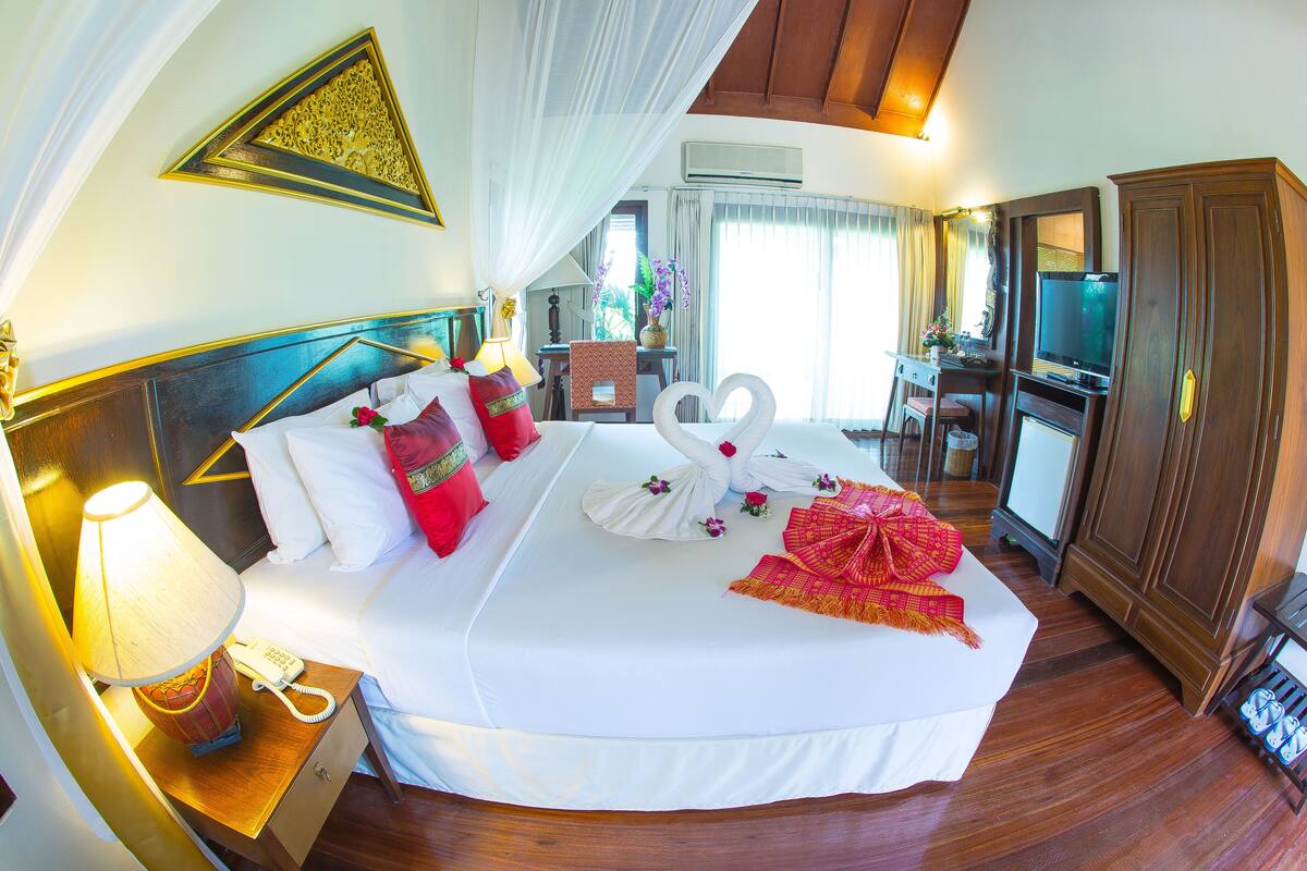 Quarto de hotel com uma cama grande, telefone ao lado da cama, luminária e guarda-roupa.