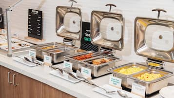 Buffet com estações de comida identificadas, incluindo ovos mexidos, torradas francesas e salsicha de peru.