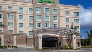 Um hotel Holiday Inn com fachada moderna, várias janelas e área de entrada coberta.