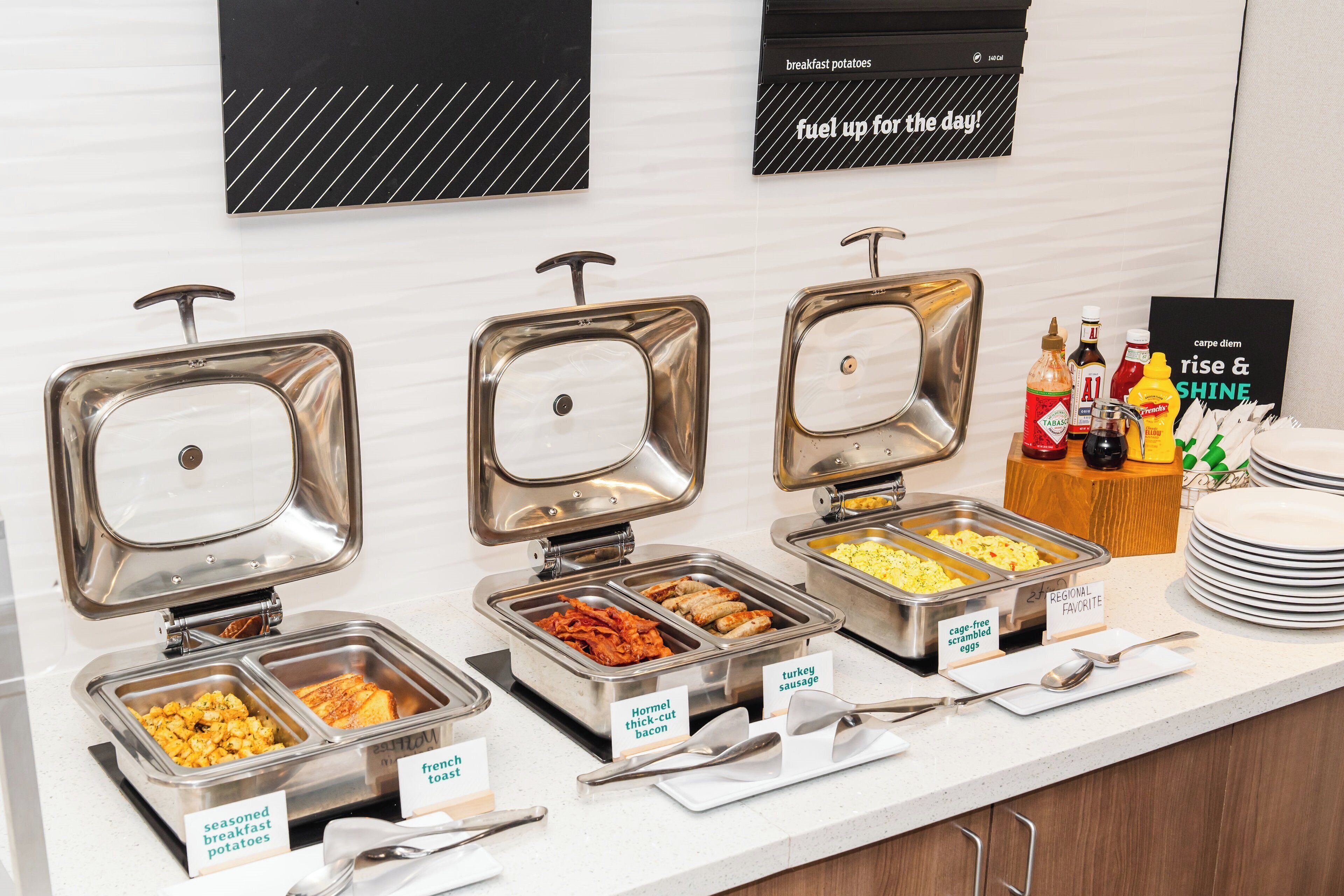 Buffet com opções de comida identificadas, incluindo batatas para café da manhã, torradas francesas e salsicha de peru.