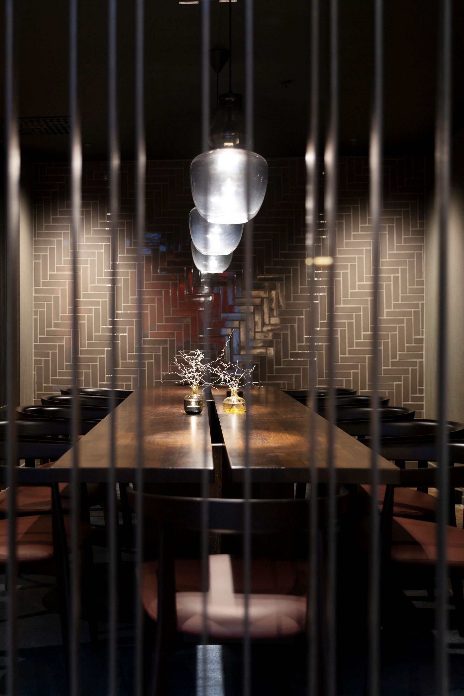 Um restaurante com uma longa mesa de madeira, cadeiras de metal e um lustre pendurado.