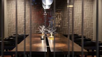 Um restaurante com uma longa mesa de madeira, cadeiras de metal e um lustre pendurado.