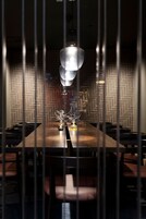 Um restaurante com uma longa mesa de madeira, cadeiras de metal e um lustre pendurado.