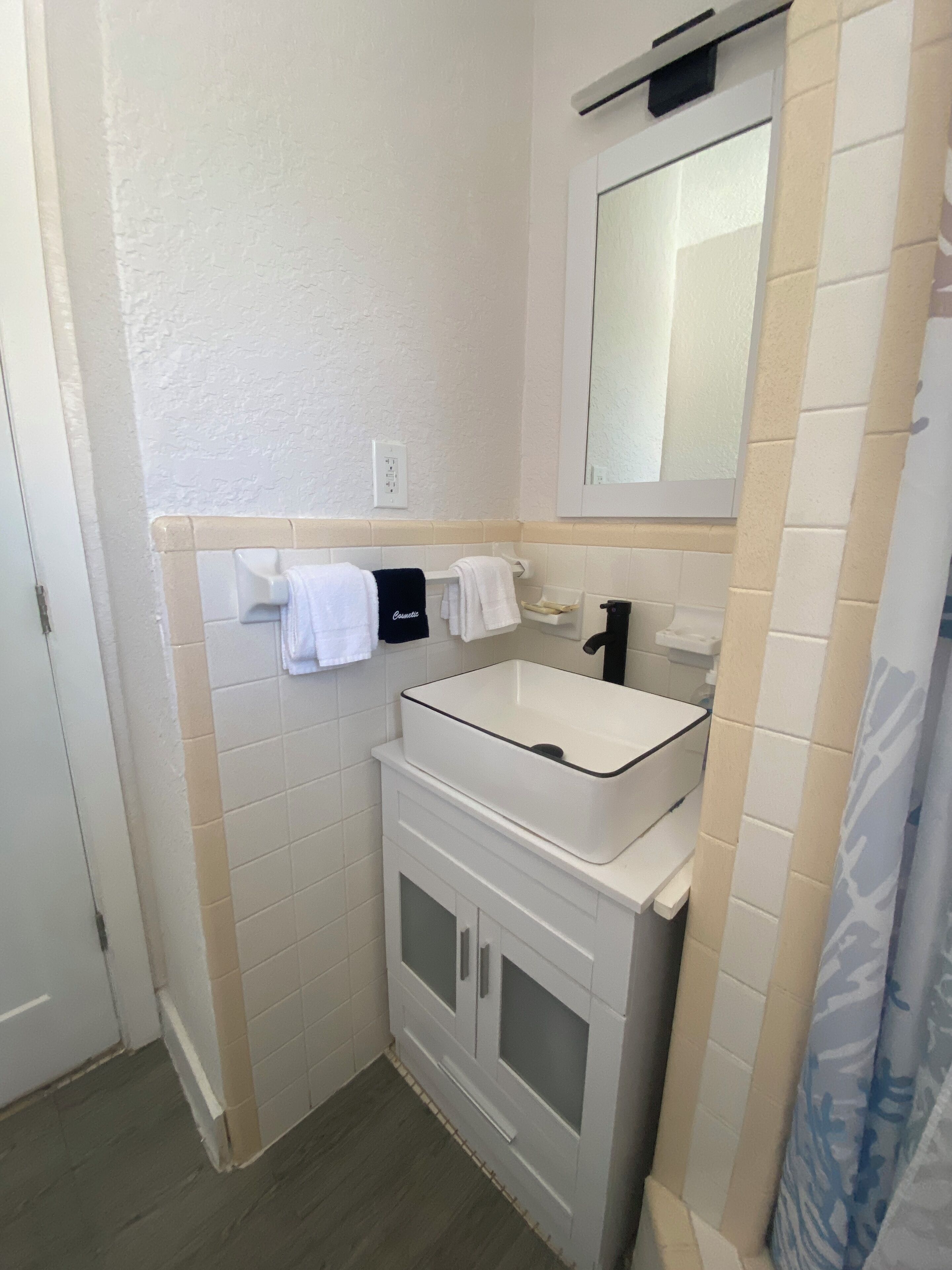 Uma casa de banho pequena com uma pia branca, um espelho e um porta-toalhas.