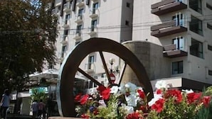 Um edifício com vários andares, varandas e uma grande estrutura circular decorativa em primeiro plano.