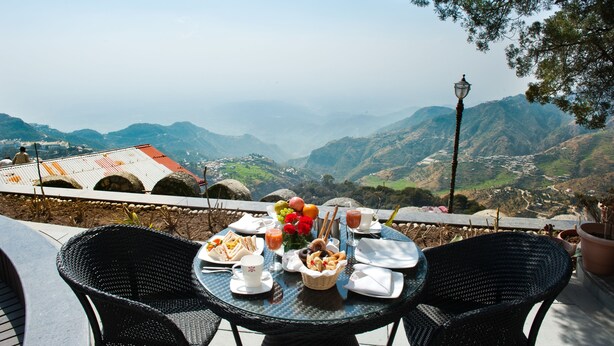 Mesa posta para o café da manhã, com vista panorâmica das montanhas.