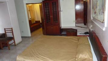Quarto com cama, guarda-roupa de madeira, cadeira e escrivaninha.