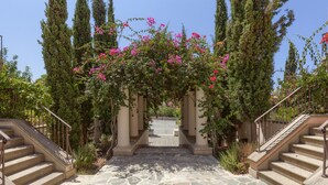 Uma escadaria de pedra leva a um espaço coberto com um arco floral.