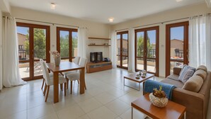 Uma sala de estar espaçosa com área de jantar, janelas amplas e uma varanda.