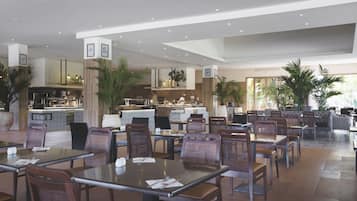 Um restaurante espaçoso com pé-direito alto, móveis modernos e uma área de cozinha central.