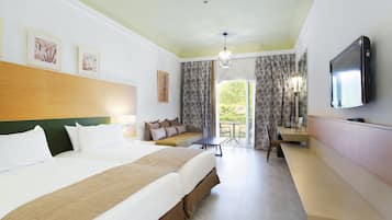 Quarto de hotel com uma cama grande, escrivaninha, cadeira, televisão e vista para o exterior.
