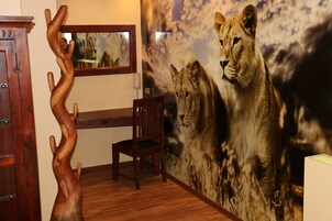 Quarto com um armário de madeira, uma cadeira de madeira e um mural de leões na parede.