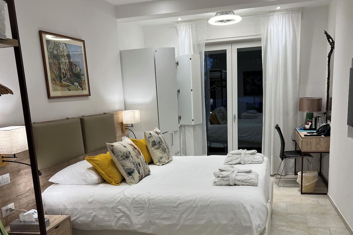 Quarto de hotel moderno com uma cama grande, mesas de cabeceira, escrivaninha e uma cadeira.