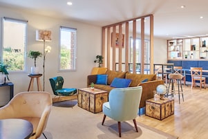 Uma sala de estar moderna com um sofá, cadeiras, uma mesa de centro e um divisória de madeira.