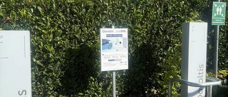 Placa com informações sobre uma área de estacionamento, cercada por vegetação e céu azul.