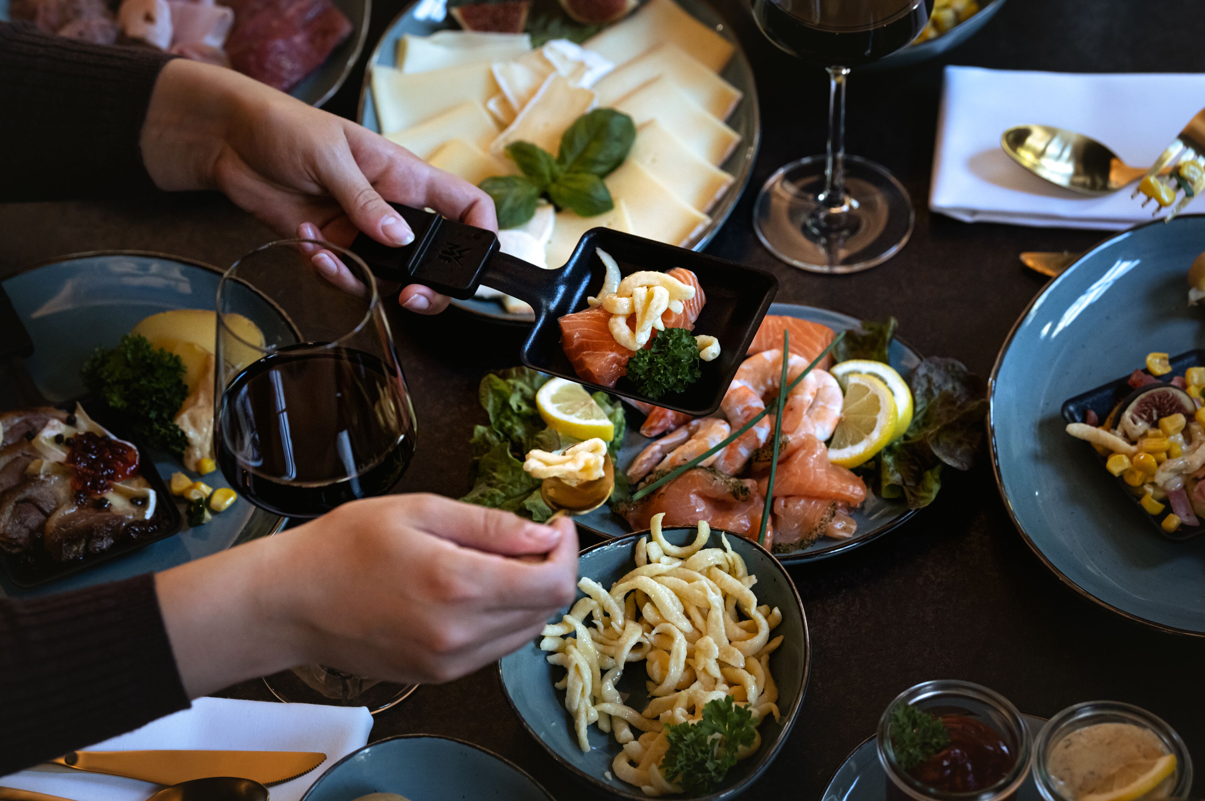 Uma mesa de jantar com diversos pratos, incluindo frutos do mar, massa e queijo.