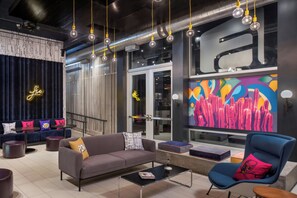 Espaço lounge moderno com sofá, poltronas, mesa de centro e luminárias pendentes.