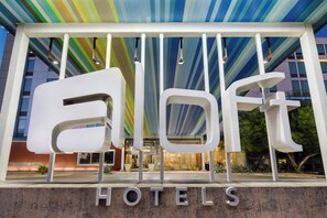 Entrada de hotel com design moderno, apresentando letras brancas grandes que formam a palavra 'HOTELS' no chão.