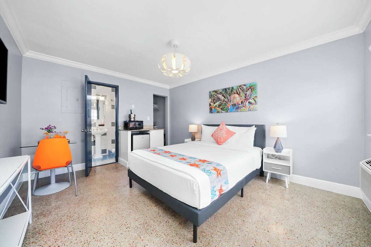 Quarto de hotel moderno com uma cama grande, uma escrivaninha e uma cadeira.