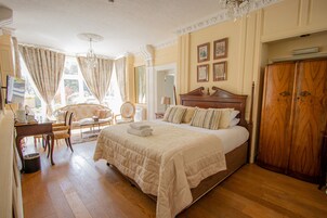 Quarto amplo com uma cama grande, guarda-roupa de madeira e um candelabro.