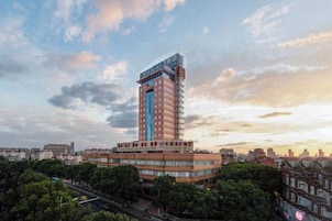 Um hotel imponente com vários andares, cercado por árvores e outros edifícios.