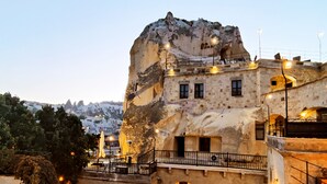 Um edifício histórico de pedra com várias varandas e arcos, apresentando uma fachada rústica e vista da paisagem circundante.