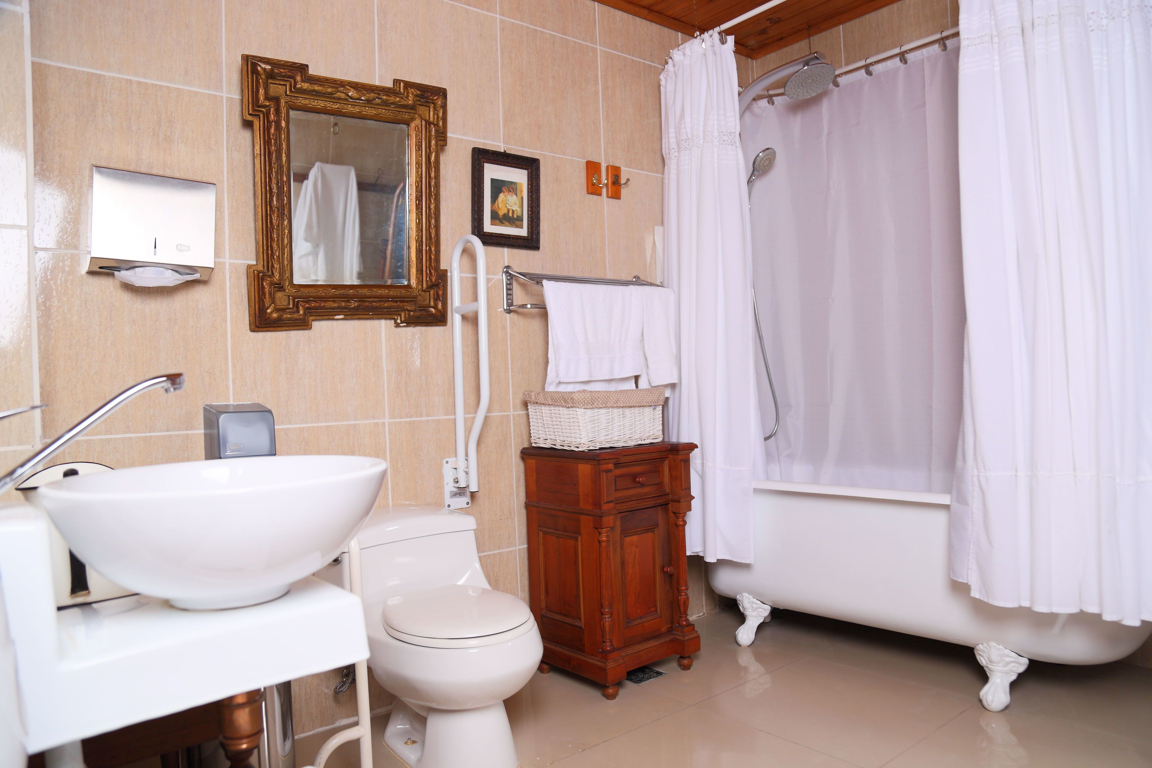 Casa de banho com lavatório branco, sanita e banheira com patas de leão.