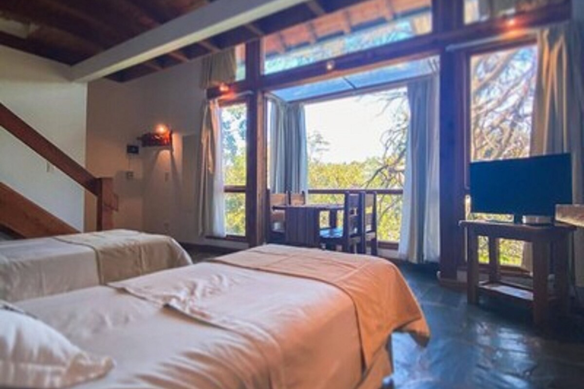 Quarto com duas camas, televisão e varanda com vista.