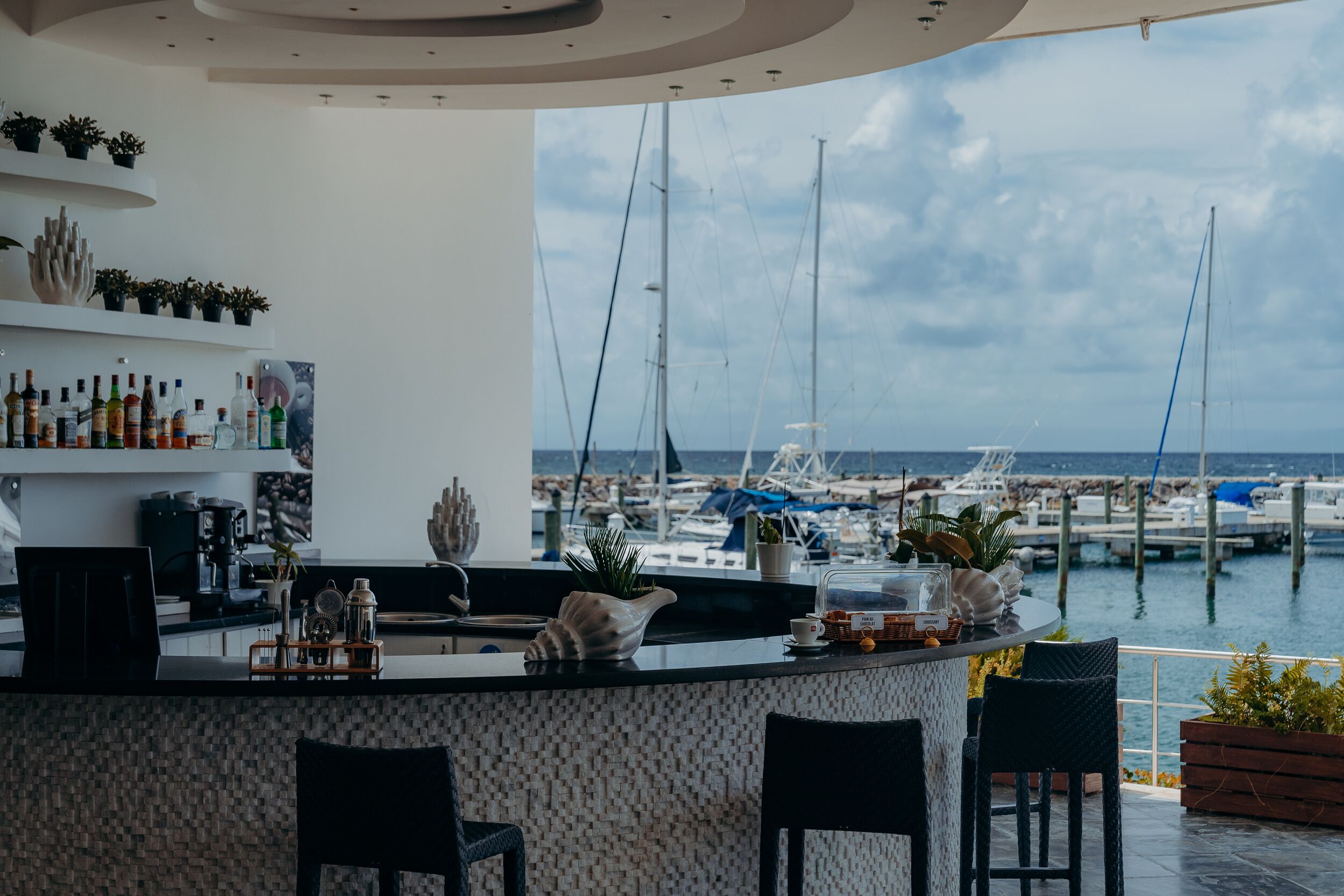 Zona de bar moderna com vista para a marina e barcos.