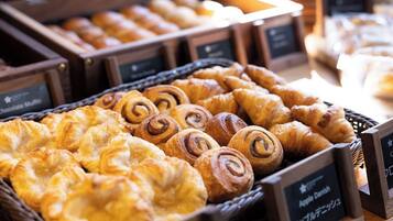 Vitrine de padaria com diversos produtos de panificação, incluindo croissants e muffins, dispostos em caixas de madeira.