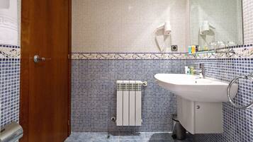 Casa de banho com lavatório branco, espelho e porta-toalhas.